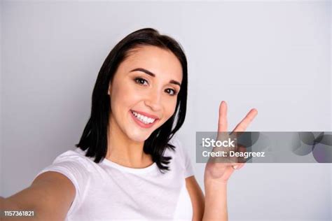 그녀의 자화상 그녀의 좋은 찾고 매력적인 사랑스러운 사랑스러운 빛나는 매력적인 쾌활한 쾌활한 기쁜 소녀 데 재미 자유 시간을 보여주는 V기호 는 밝은 회색 파스텔 배경을