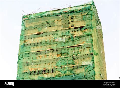 tall building with bamboo scaffolding and covered in tattered ripped