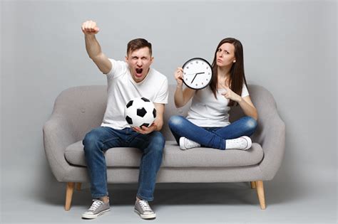 커플 여자 남자 축구 팬을 비명을 지 원하는 축구 공을 좋아하는 팀을 응원 라운드 시계를 들고 회색 벽 배경에 고립 된 주먹을 쥔 스포츠 가족 레저 라이프 스타일 개념입니다