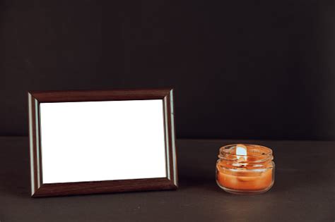 불타는 촛불 옆의 검은 색 손상에 대한 짙은 갈색의 빈 사진 프레임 맑은 유리 병에 붉은 불이 켜진 촛불 나무 직사각형 사진 프레임의 수평 배치 0명에 대한 스톡 사진 및
