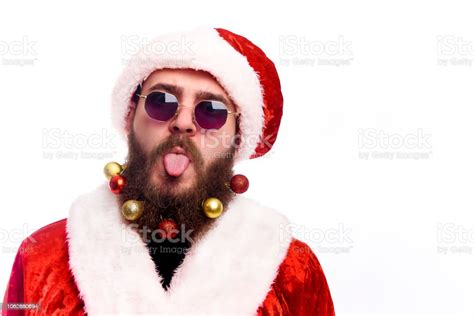 젊은 남자가 입고 산타 클로스 수염에 크리스마스 장식과 흰색 배경에 그의 혀를 보여줍니다 12월에 대한 스톡 사진 및 기타 이미지 12월 감정 공휴일 Istock