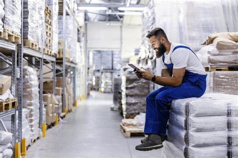 보관 직원은 밀가루가 든 가방 더미에 앉아 태블릿을 사용하여 주문을 확인하고 있습니다 홀짝이는 주문은 단 하루 만에 고객에게 도착할 수 있습니다 사진 Unsplash