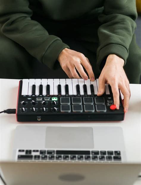 Man Recording Electronic Music Track With Portable Midi Keyboard On Laptop Computer In Home