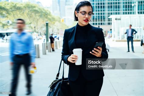 휴대 전화에 대한 알림에 대한 텍스트 Sms를 읽고 배경 에 사무실 건물과 현대적인 거리에 걷는 우아한 옷을 입은 진지한 여성 온라인 파트너와 채팅 여성 무역 전문가