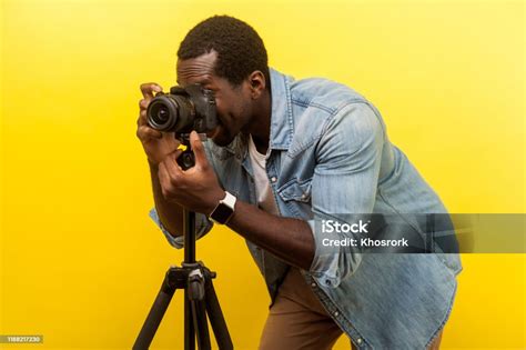 삼각대에 전문 디지털 Dslr 카메라와 함께 사진을 찍는 행복 한 사진 작가의 초상화 노란색 배경에 고립 된 실내 스튜디오 샷 사진작가에 대한 스톡 사진 및 기타 이미지