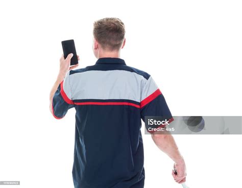 리어 뷰 1인 허리 까지 2029세 성인 잘생긴 젊은 남성 남성 정비사 자동 정비사 수동 작업자 수리공 앞 흰색 배경 유니폼을 입고 스마트폰 문자 메시지를 사용 하 여 20