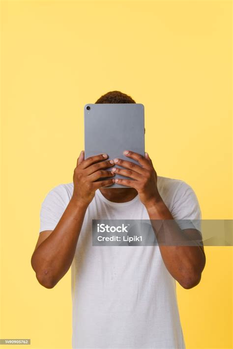 익명성 시크릿 온라인 개념 태블릿 Pc를 손에 들고 있는 익명의 아프리카계 미국인 밝은 노란색 배경에 숨겨진 얼굴이 격리되어 있으며 디자이너가 자신의 텍스트나 그래픽을