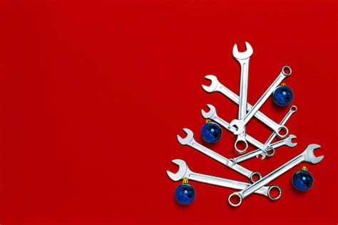 빨간 배경에 파란색 공으로 장식 된 렌치로 만든 크리스마스 트리 도구가 있는 새해 배너 인사말 텍스트를 위한 장소가 있는 엽서입니다 새해 복 많이 받으세요 산업 휴가 개념