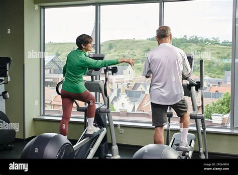 Active Seniors Woman Pointing At Stepper Exercise Machine Near Elderly Man Senior Couple