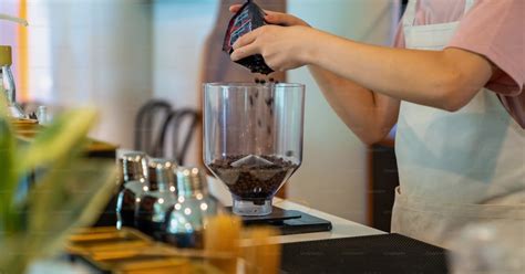 아시아 남자 커피 숍 파트 타임 직원은 커피 머신에서 뜨거운 커피를 양조합니다 커피 메이커에서 분쇄 커피로 에스프레소를 만드는 남성 바리스타 중소 기업 소유자와