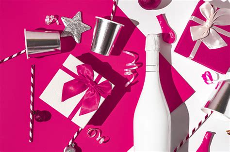 흰색 샴페인 병으로 만든 크리스마스 구성 선물 상자 빨대가있는 실버 종이 안경 밝은 분홍색 장식 및 풍선 축제와 파티 개념 배경 맨 위 보기입니다 플랫 레이 2022년에