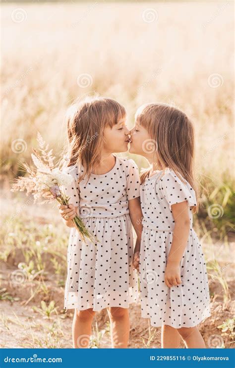 Two Little Happy Identical Twin Girls Playing Together In Nature In