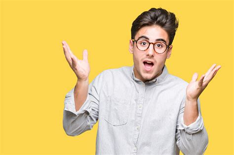 젊은 잘생긴 남자에 안경을 절연 배경 미친을 축 하 하 고 무기와 성공을 위한 흥분 비명 제기 및 오픈 눈 깜짝 놀라게 우승자 개념 긍정적인 감정 표현에 대한 스톡 사진 및