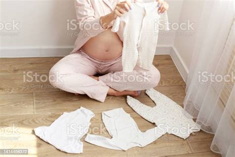 톱 뷰 임신 한 어머니는 손에 아기 옷을 들고 행복한 기대 어머니는 아이를 기다리고 있습니다 출산 준비 소녀 큰 배 고급 임신 모성 개념 30 34세에 대한 스톡 사진 및