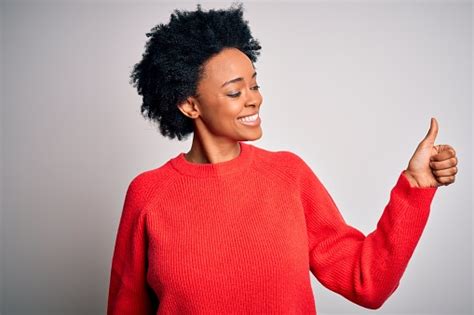 젊은 아름다운 아프리카 계 미국인 Afro 여자 와 곱슬 머리 입고 빨간 캐주얼 스웨터 찾고 자랑스러운 웃고 있는 엄지 손가락