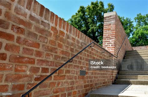 붉은 계단은 공원 경로가있는 풀밭의 지형 아래로 내려갑니다 벽은 가공 된 벽돌 블록과 콘크리트 계단으로 만들어집니다 측면에 할로겐이있는 백라이트 계단 0명에 대한 스톡 사진