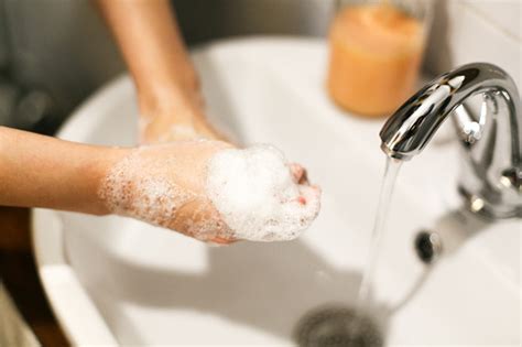 손을 씻는다 욕실에서 흐르는 물의 배경에 비누 거품으로 씻는 손 손바닥을 문질러 독감 질환의 예방 개인 위생 코로나바이러스