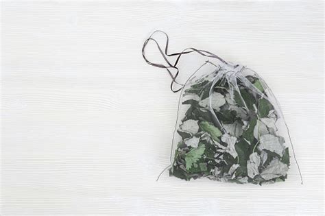 흰색 나무 배경에 에코 천연 가방에 허브 차를 양조하기위한 유용한 향기로운 허브 섬유 가방에 블랙 커런트의 말린 젊은 잎