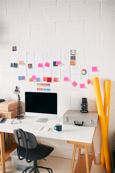 Workspace In Creative Studio With Desk And Computer In Front Of Wall With Fashion Designs Stock