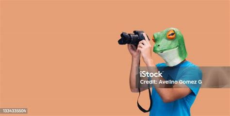 복사 공간이있는 주황색 배경의 렌즈를 통해 보는 포토 저널리스트로서 카메라로 개구리 마스크 제스처를 하는 사람 사진작가에 대한 스톡 사진 및 기타 이미지 Istock