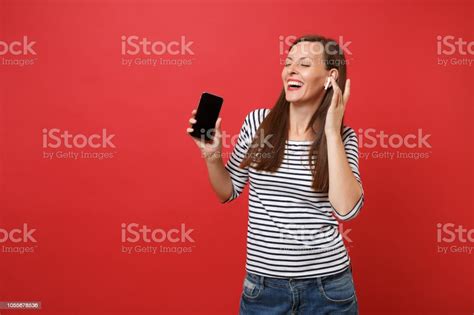 무선 이어폰 쾌활 한 젊은 여성이 빈 블랙 빈 화면 듣는 음악 빨간색 배경에 고립 휴대 전화 만요 사람들이 진심으 감정 라이프
