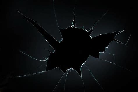 검정색 배경에 구멍이 있는 깨진 깨진 유리 프리미엄 사진
