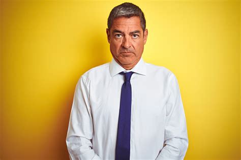 고립 된 노란색 배경 회의론자와 긴장 때문에 문제의 눈살을 찌푸리게 화가 위에 서 잘 생긴 중년 사업가 부정적인 사람 감정에