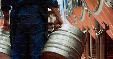 작업복을 입은 현대 맥주 생산 공장의 남성 노동자가 거대한 강철 탱크의 줄을 따라 이동하는 동안 두 개의 수조를 들고 있는 뒷모습 사진 Unsplash의 통 이미지