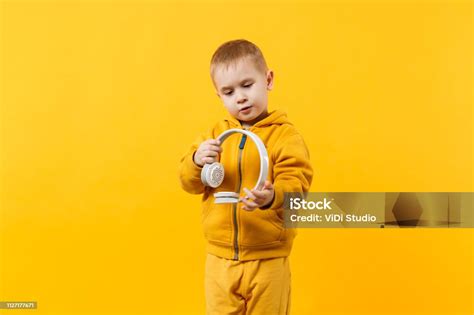 작은 아이가 소년 34 년 된 헤드폰에 노란색 옷을 입고 오렌지 벽 배경 어린이 스튜디오 초상화에 고립 사람들이 진심으 감정 어린 시절 라이프 스타일 개념 복사 공간을 모의