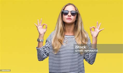 격리 된 배경 위에 젊은 아름 다운 금발의 여 자가 입고 선글라스 휴식과 명상 손가락으로 제스처를 하 고 폐쇄 눈으로 웃 고