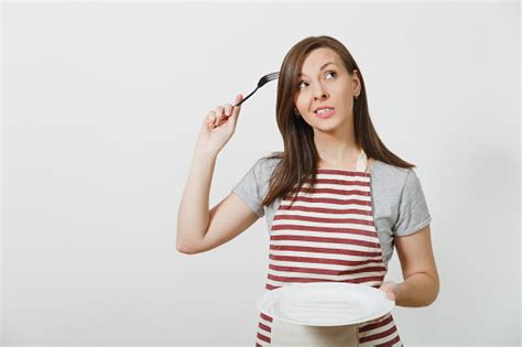 영 재미 스트라이프 앞치마가 정부 여자 들고 흰색 빈 접시 포크 처럼 머리에 흰색 배경에 고립 된 회색 티셔츠에 미친 갈색 머리 주부 빗 빗 광고에 대 한 공간을 복사 가사