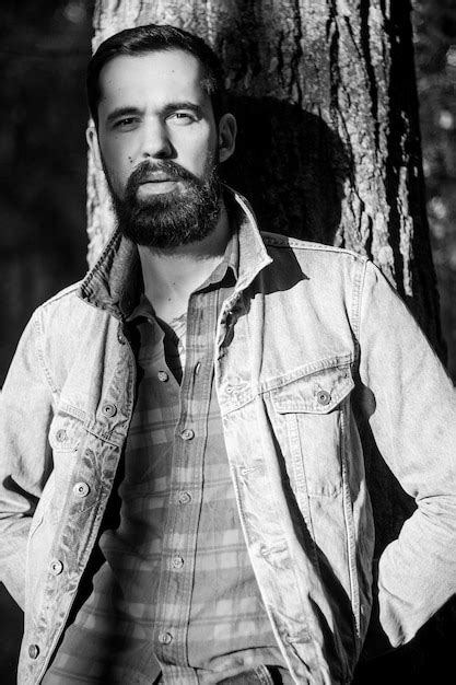 Premium Photo Portrait Of Bearded Young Man Standing Against Tree Trunk