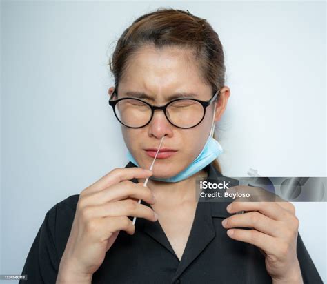 Asian Woman Using Rapid Antigen Test Kit By Nasal Swab Herself For