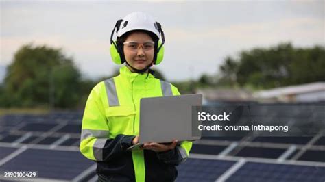 녹색 안전 재킷을 입고 귀마개를 착용하고 노트북을 들고 태양열 발전소 현장에서 일하는 여성 에너지 엔지니어의 초상화 검사 보기에 대한 스톡 사진 및 기타 이미지 Istock