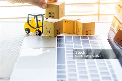 노트북 키보드와 미니 지게차 트럭에 카트 기호에 추가 골판지 상자를 들고 손가락 물류 및 운송 관리 아이디어 및 산업 비즈니스 상업 개념 고객에 대한 스톡 사진 및 기타