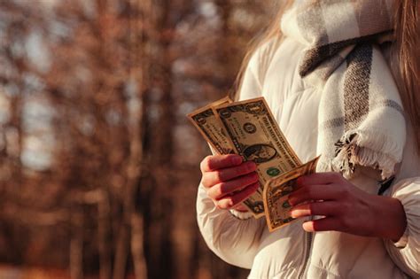 가을 공원 배경 야외에서 현금 달러를 들고 흰 옷을 입은 소녀 손을 닫습니다 팔 젊은 이익 아가씨 돈으로 지불 은행 지불 개념입니다 광고용 텍스트 공간 복사 1 달러 지폐