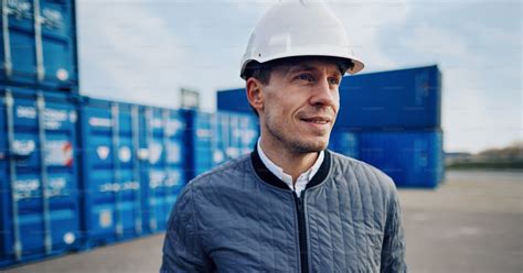 안전모를 쓰고 클립보드를 들고 대형 상업용 부두에 혼자 서 있는 웃는 엔지니어 사진 Unsplash의 제조업 직종 이미지