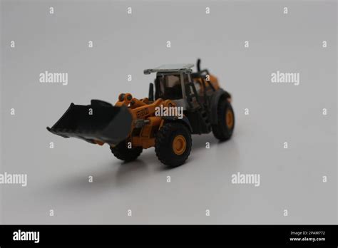 A Close Up Of Miniature Orange Wheel Loader Toy Isolated On White