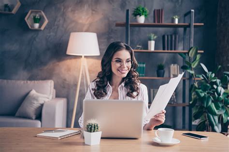 빛나는 매력적인 여자의 사진 입고 줄무늬 셔츠 안경 앉아 테이블 채팅 현대 장치 찾고 종이 실내 방 곱슬 머리에 대한 스톡 사진 및 기타 이미지 Istock