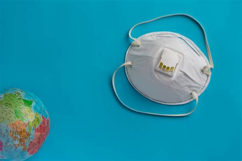 세계 코로나 바이러스 2019ncov 공격 개념 근처의 흰색 의료 마스크는 지구 세계 파란색 배경에 행성의 모델입니다 오염 바이러스 독감 및 코로나 바이러스에 대한 얼굴