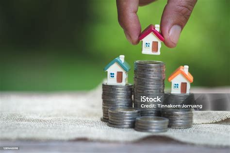 동전 스택에 여자의 손 퍼팅 집 모델 부동산 사다리에 대한 개념 주택 개념 부동산 모기지 및 주택에 대한 투자를 구입하는 동전의