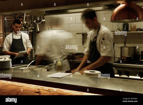 Two Chefs In A Kitchen Behind The Counter Are Working Together To