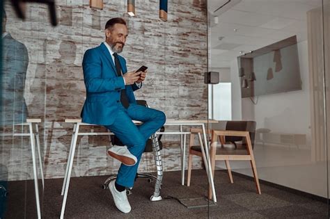Premium Photo Happy Adult Man Sitting On Desk And Using Smartphone