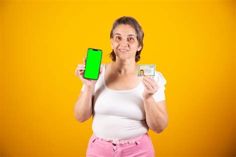 Premium Photo Adult Brazilian Woman Holding Identity Card Id Card And Smartphone With Green Screen