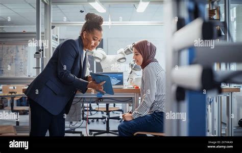Black Senior Engineer Discussing Robotic Arm With Promising Arabic Female Computer Scientist