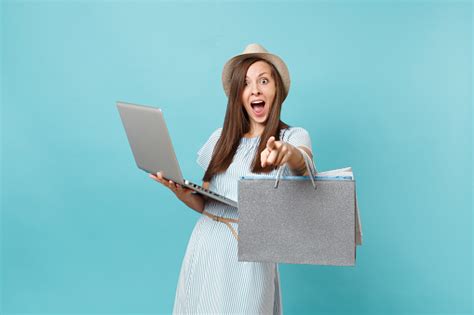 여름 드레스 온라인 쇼핑 후 구매와 패키지 가방을 들고 밀 짚 모자에에서 젊은 여자의 초상화 블루 파스텔 배경에 고립 된 노트북 Pc 컴퓨터를 사용 합니다 광고에 대 한