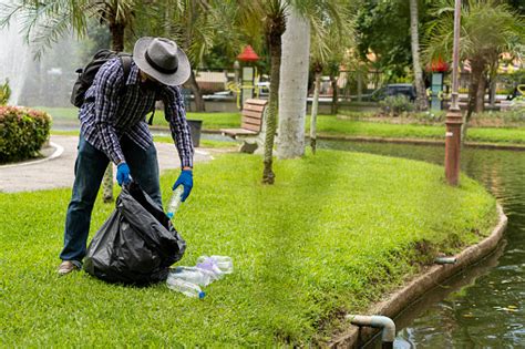 자원봉사자들은 공공 공원 주변의 쓰레기 봉투에 플라스틱 병을 수거합니다 환경 보호 및 글로벌 오염의 바닥 개념에 쓰레기를 수집 큰 검은 가방을 들고 남자 35 39세에 대한