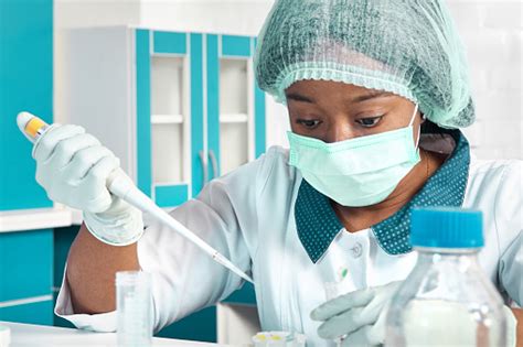 흰색 코트 보호 모자 및 장갑을 착용한 아프리카 과학자 기술 보조 자 또는 의료 기술자는 의료 테스트 실험실에서 새로운 코로나