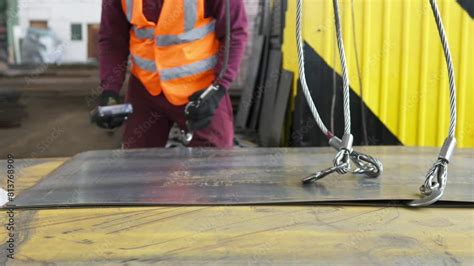 A Worker Moves Large Industrial Metal Parts Using A Remote Controlled Overhead Crane To A Cnc
