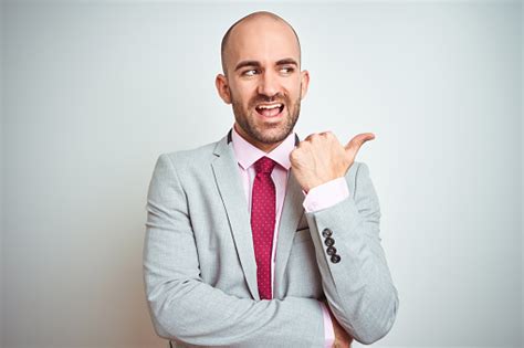 양복과 보라색 넥타이를 입고 고립 된 배경 위에 행복한 얼굴을 보고 엄지 손가락으로 옆을 가리키는 젊은 사업가 가리키기에 대한 스톡 사진 및 기타 이미지 Istock